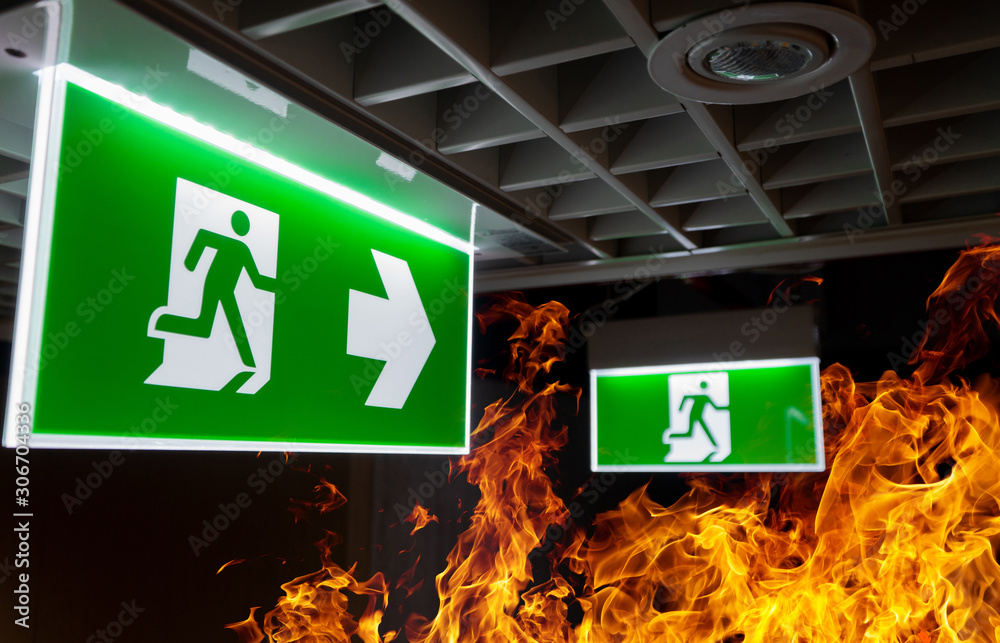 Hot flame fire and green fire escape sign hang on the ceiling in the ...