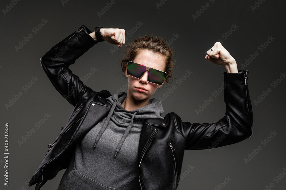 A young girl with rough facial features in a black jacket shows her ...