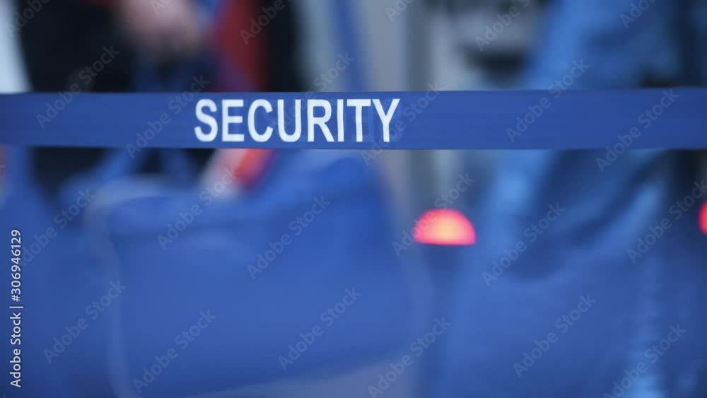 Writing security on blue tape barrier at airport. People standing in ...