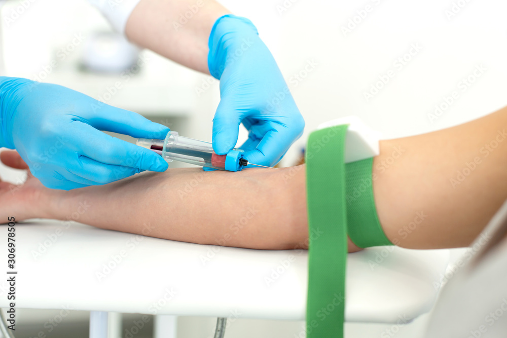 a gloved nurse inserts a needle into a vein on the patient arm and ...