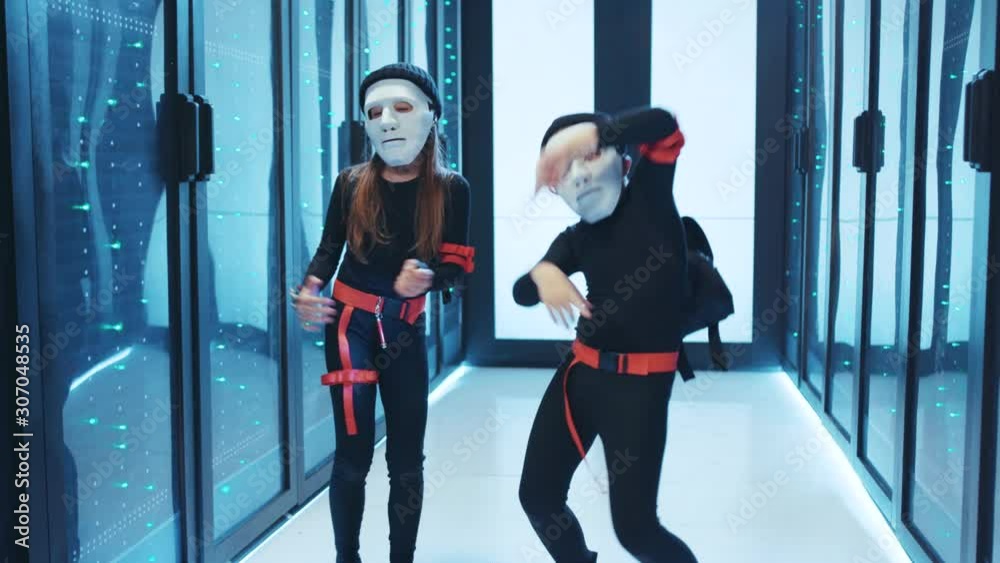 Masked anonymous kids in black spy costumes dancing in middle of server ...