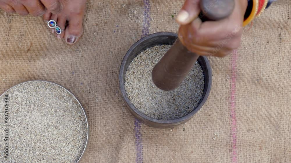 Vídeo do Stock: Top view of a woman beating millet / bajra with mortar ...