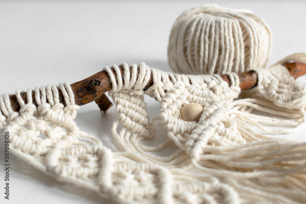 Handmade macrame braiding and cotton threads on rustic wooden stick ...