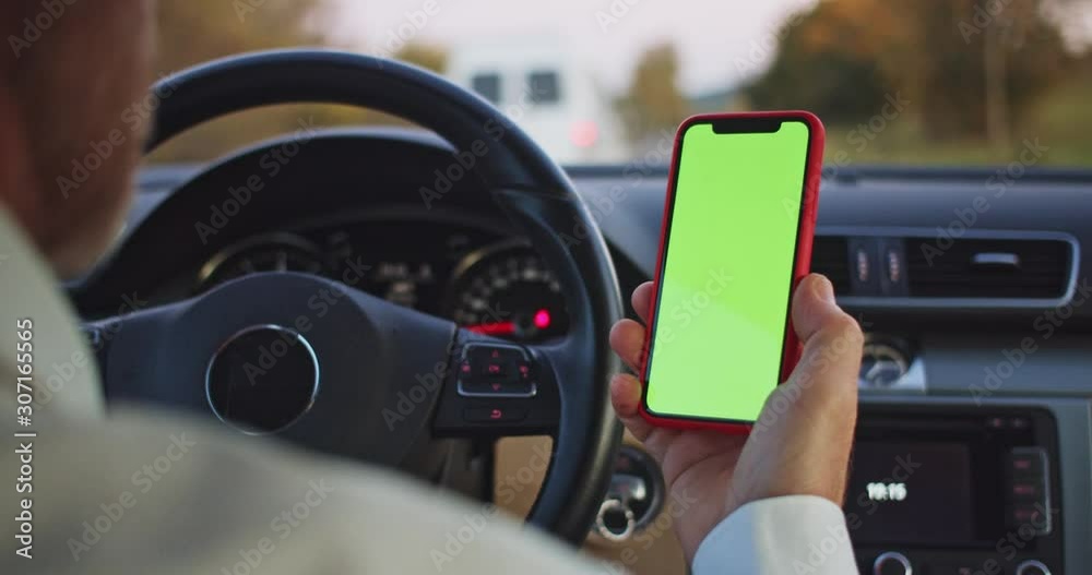 Male driver hand holding smartphone with blank green screen in luxury ...