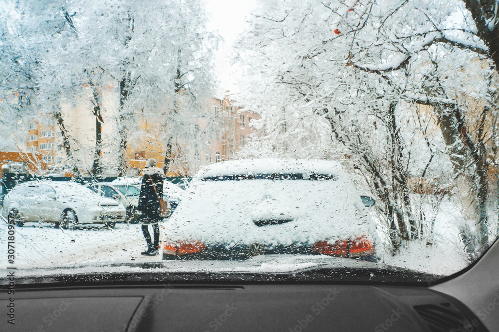 A pedestrian crosses the street in a snowstorm in front of the car ...