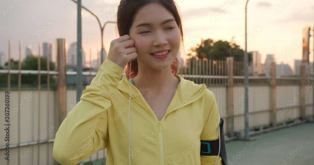 Beautiful young Asia athlete lady exercises using smartphone for listen ...