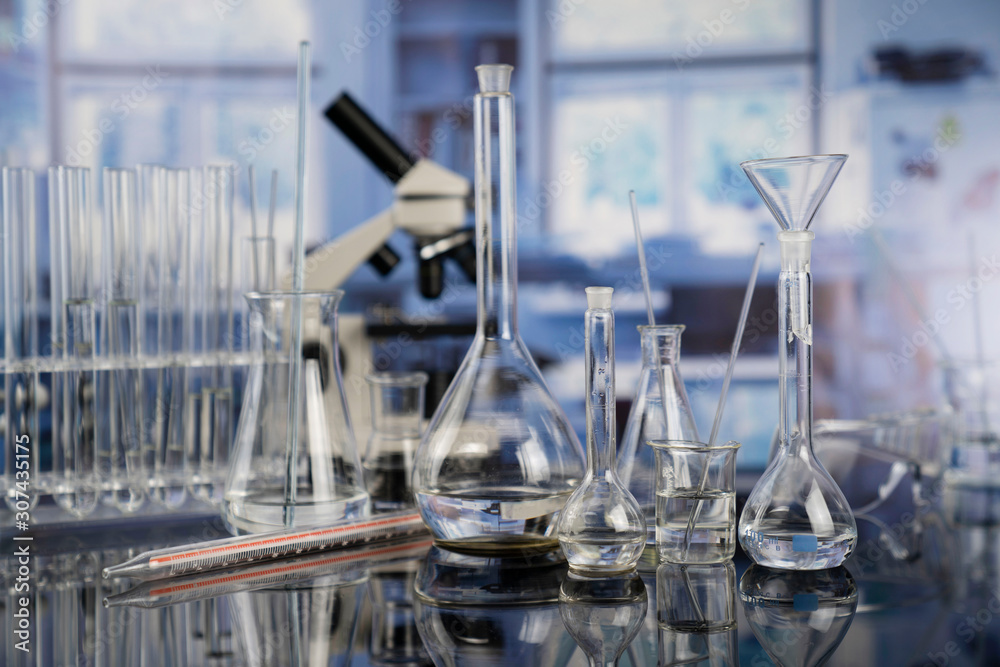 Science laboratory. Beakers, test-tubes and microscope on glass table ...