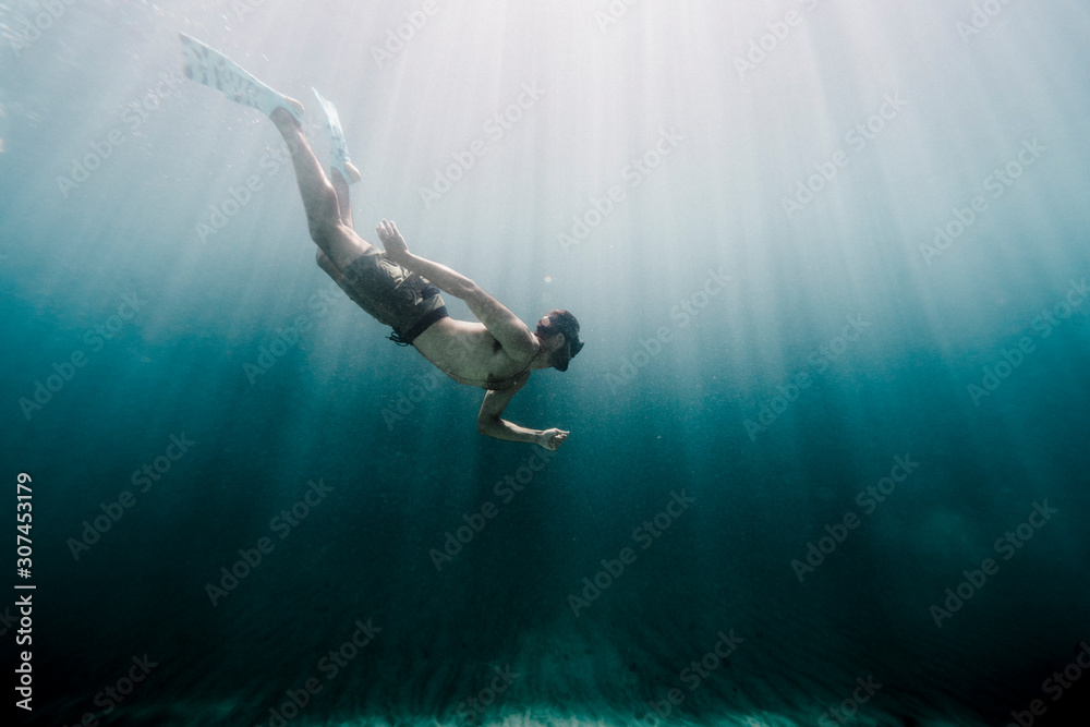 Side view of man swimming underwater in ocean Stock Photo | Adobe Stock