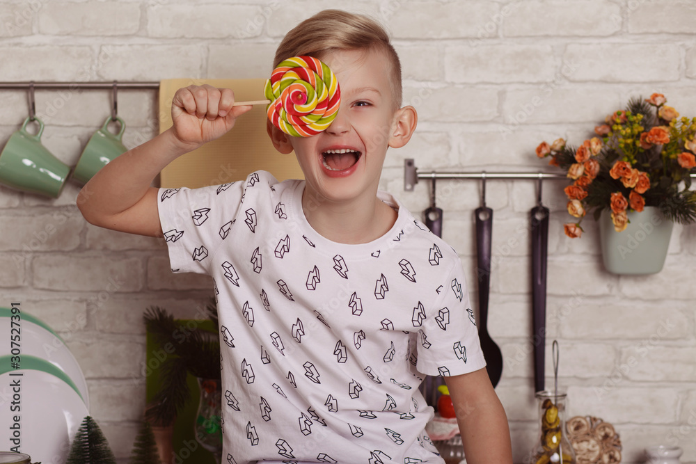 Beautiful little blond boy is sitting on the kitchen table with a big ...