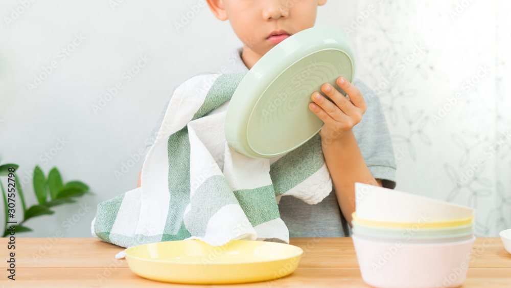 Adorable little kindergarten child, boy dry dishes with care, focus and ...