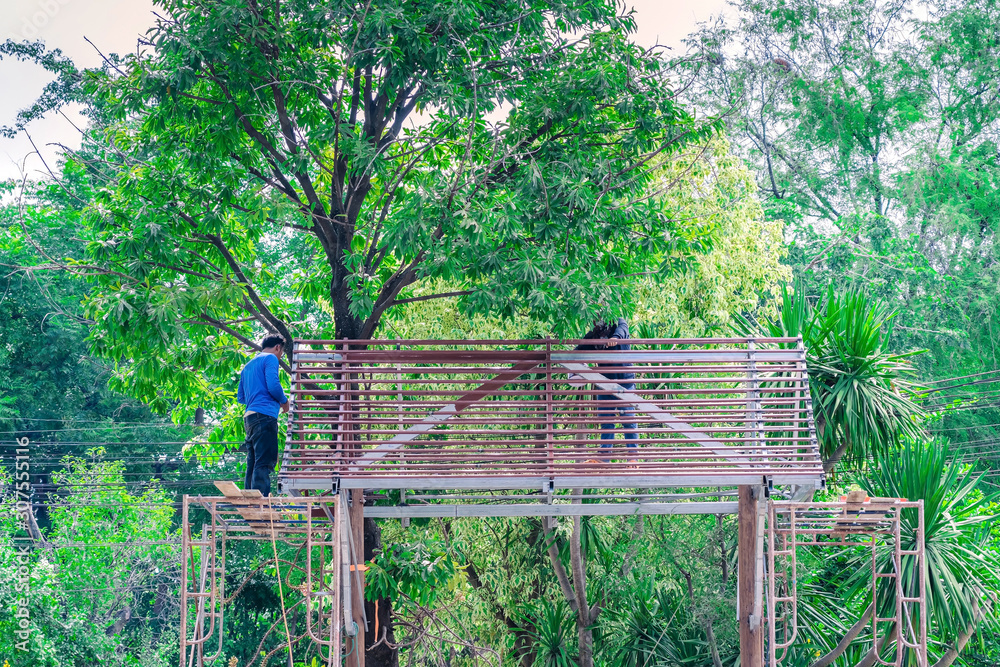 Welder and painter are helping to build a gable roof structure below a ...