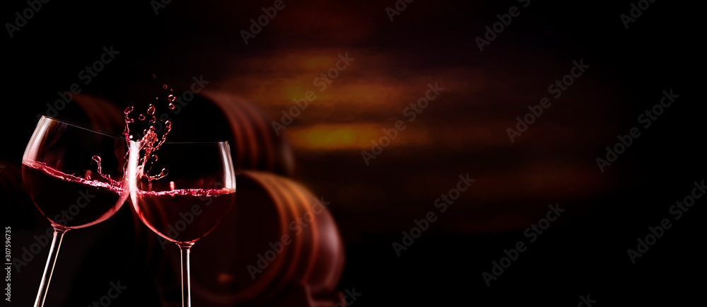 Glasses with red wine toast, in the dark background are wine barrels ...