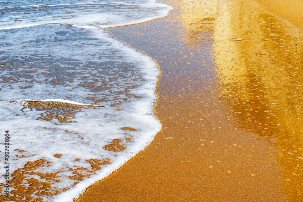 Soft moving sea waves foams and cliffs reflections in wet sandy beach ...