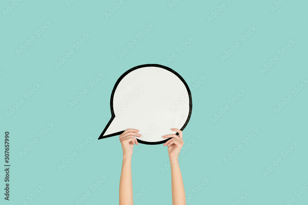 Hands holding the sign of comment on blue studio background. Negative ...
