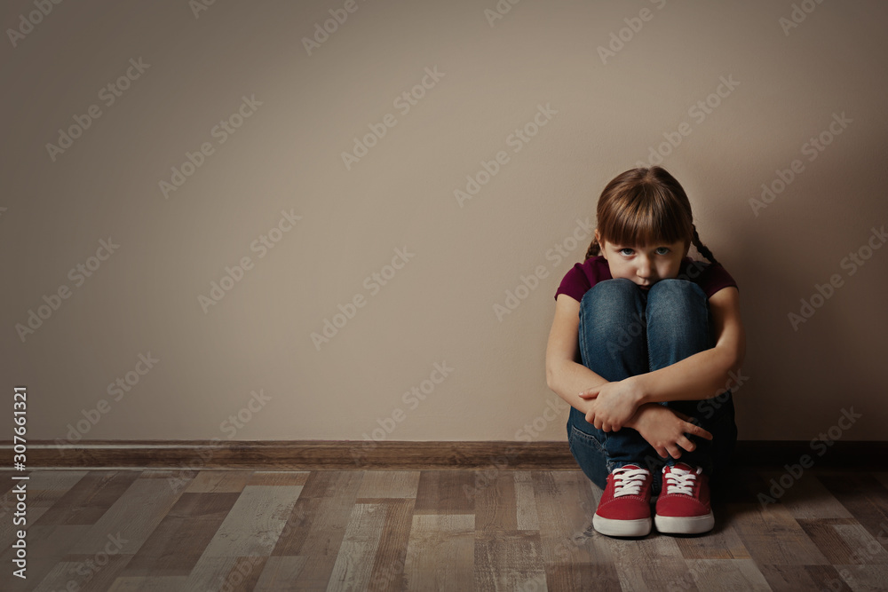 Sad little girl sitting on floor indoors, space for text. Child in ...