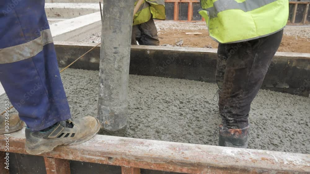 Pouring concrete mix from cement mixer on concreting formwork. Finished ...