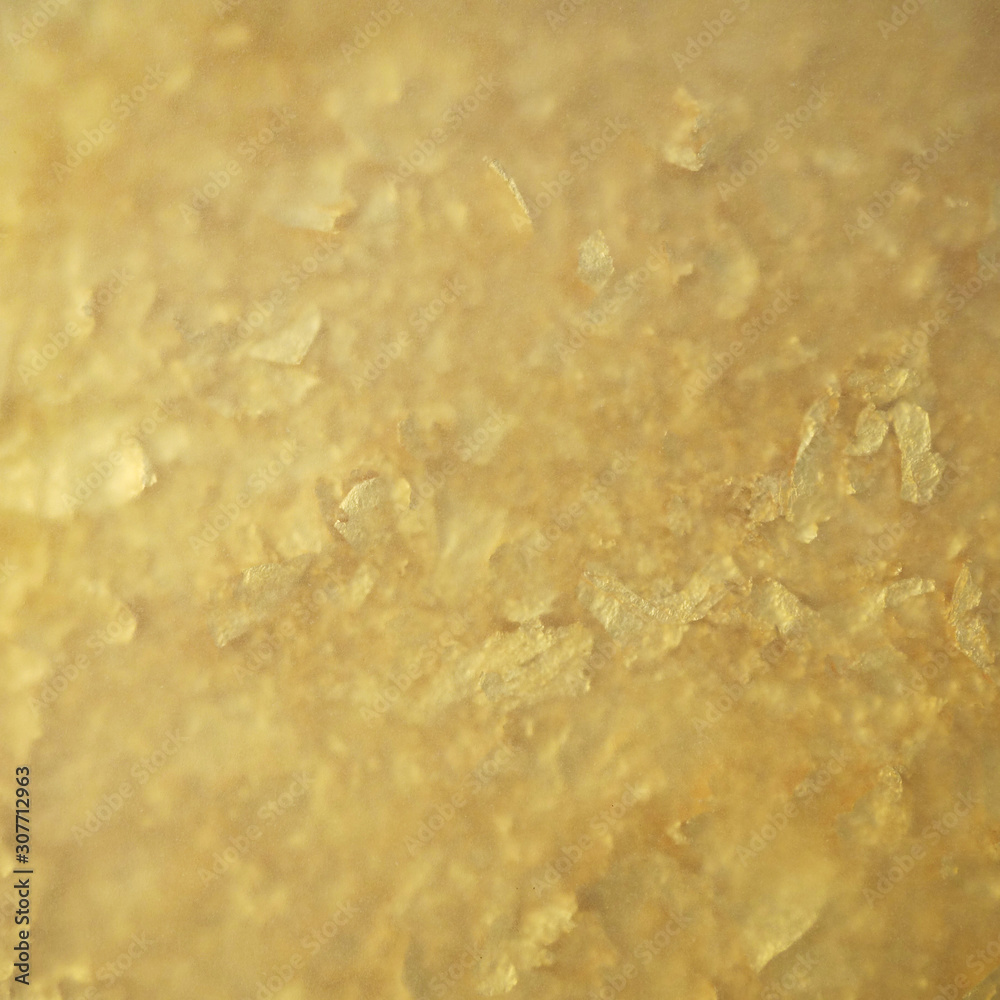 Gold flakes under a transparent tracing paper, golden unusual texture ...