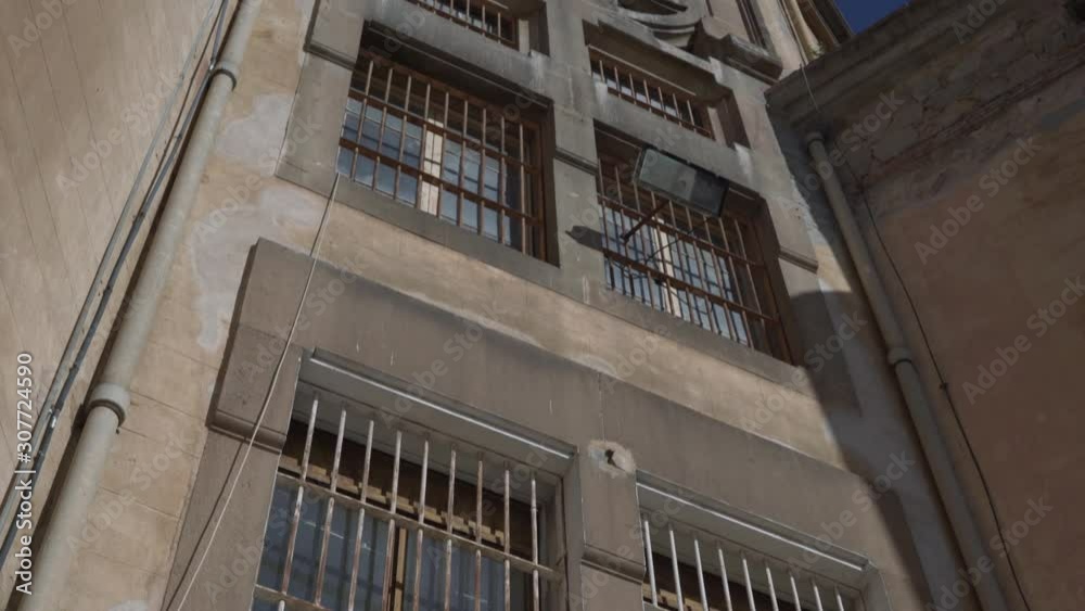facade of the prison building with spotlight on wall and bars on ...