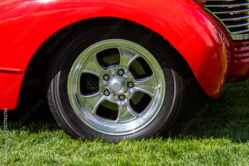 Old classic American bright red car wheel on the grass, chrome star rim ...