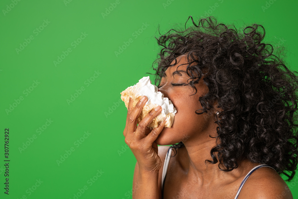 Attractive black woman taking messy bite of cake on greenscreen Stock ...