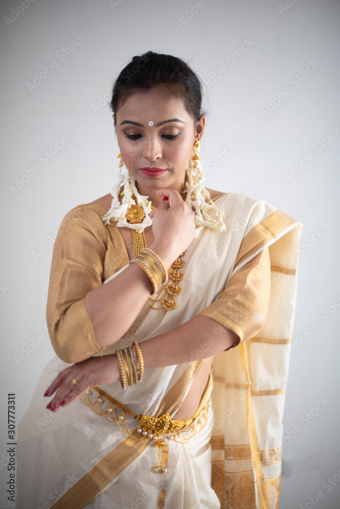 An young and attractive Indian woman in white traditional wear dancing ...