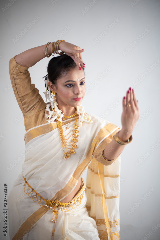 An young and attractive Indian woman in white traditional wear dancing ...