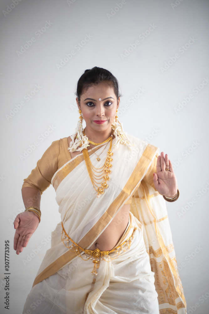 An young and attractive Indian woman in white traditional wear dancing ...