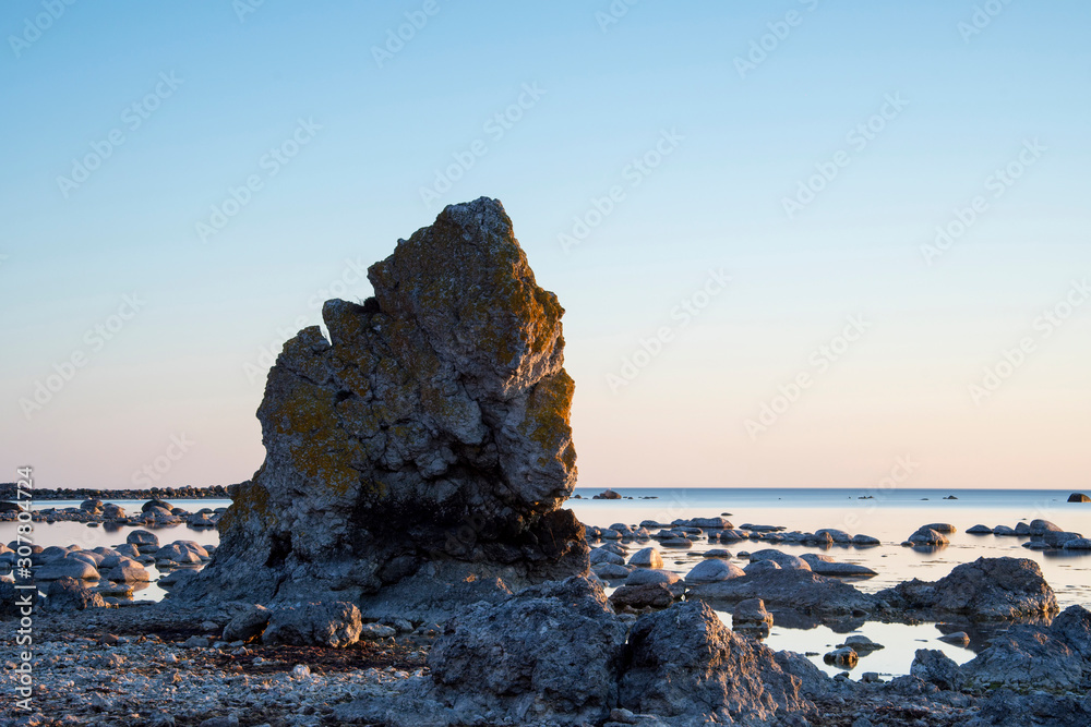 Eroded limestone stack with vibrant summer ocean sunset background at ...