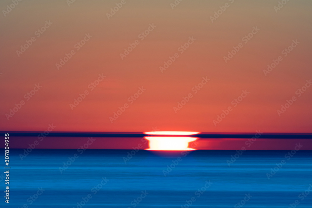 Vibrant sunset reflection in mirror like blue ocean, outside island of ...
