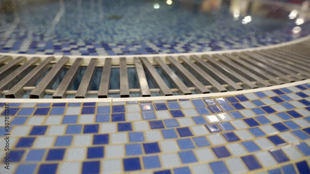 Close up side blue mosaic tiles water drain system in the pool of the ...