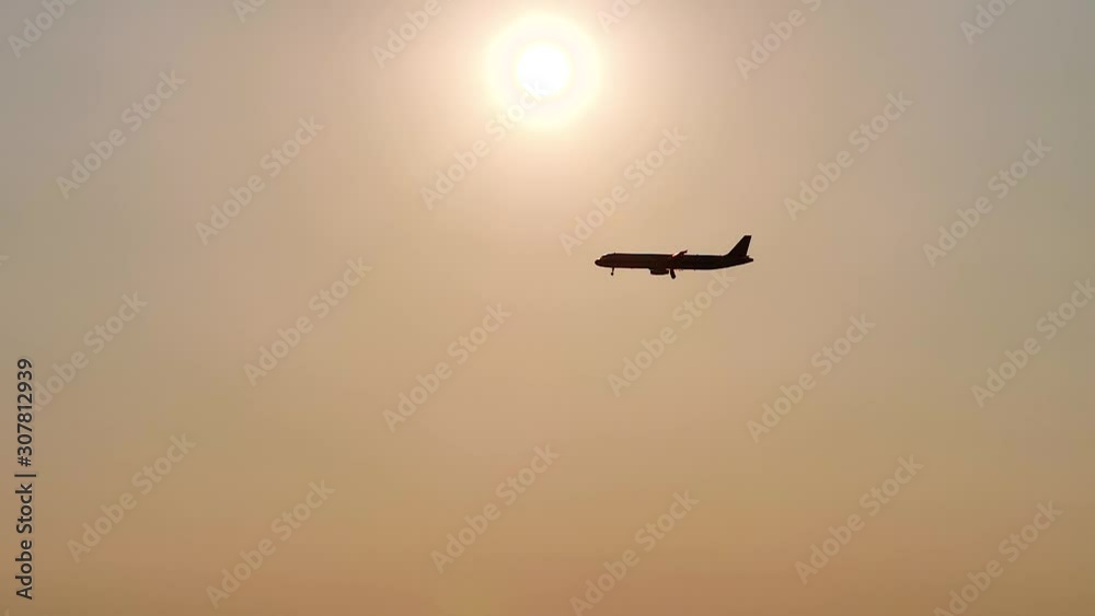 Landing airplane flying under the sun during sunset time, silhouette ...