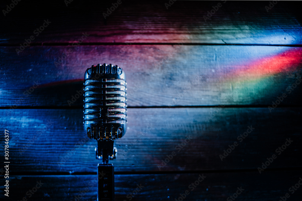 Retro microphone on wooden background and color lights with copy space ...
