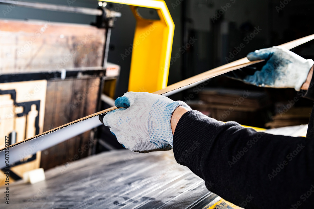Placing a carton in a punching machine. Cardboard boxes production ...