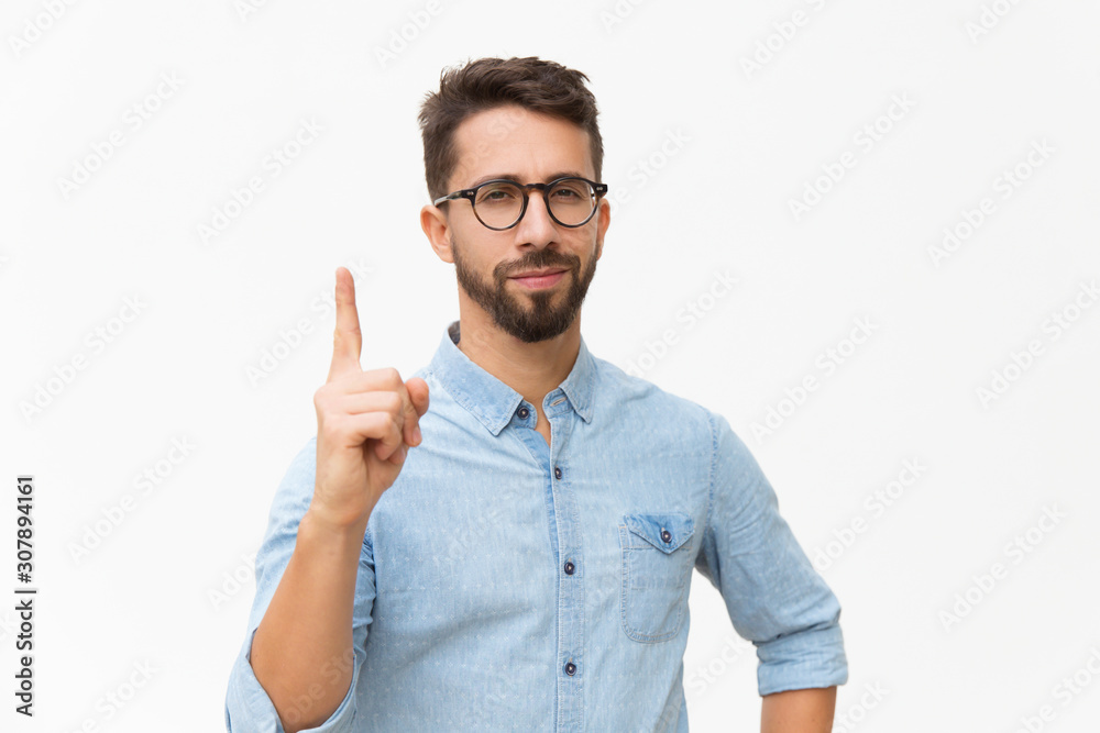 Positive friendly guy having idea and pointing index finger up ...