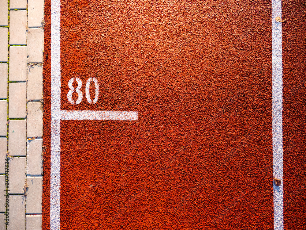 Shot from above of the red running track with the number 80. A piece of ...