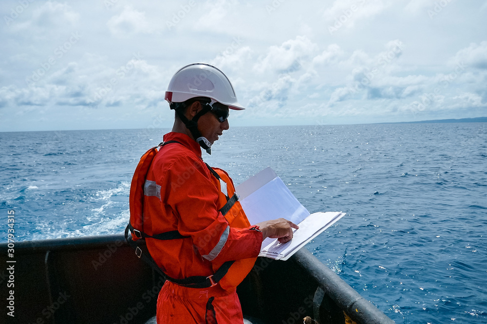 Safety officer, standing on an industrial ship, wearing overalls, a ...