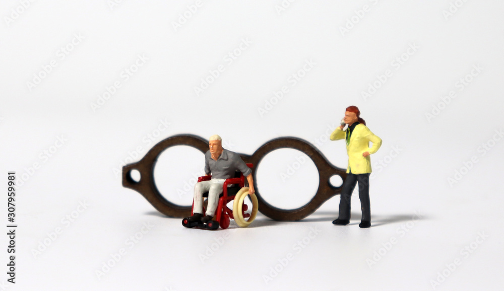 A miniature man in a wheelchair and a miniature man standing in front ...