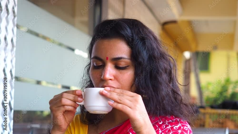 indian woman drinking masala tea with milk and spices ,she wearing gold ...