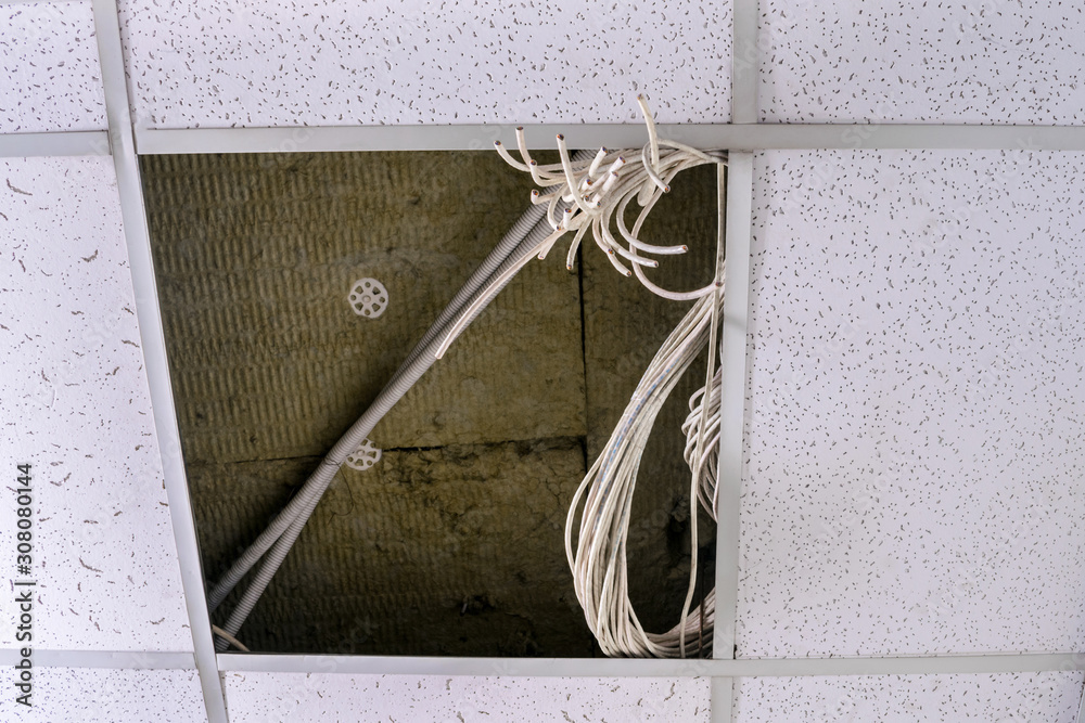 There are dangling white cables above the false ceiling. Electrical ...