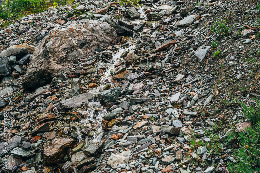 Clear spring water flows on beautiful stony steep slope. Boulder stream ...