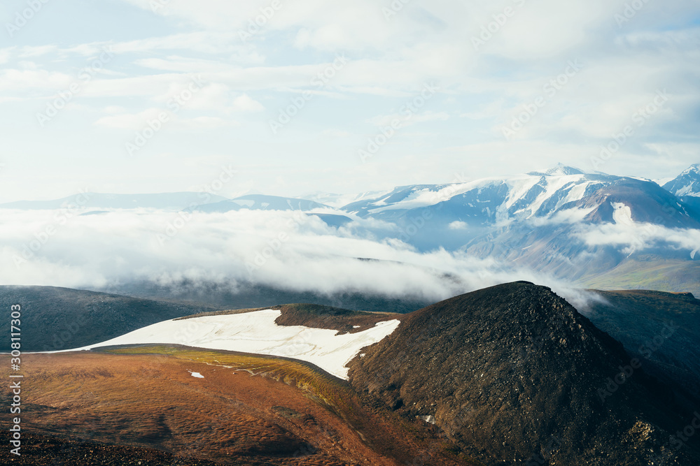 Atmospheric alpine landscape with giant low cloud above rocky mountain ...
