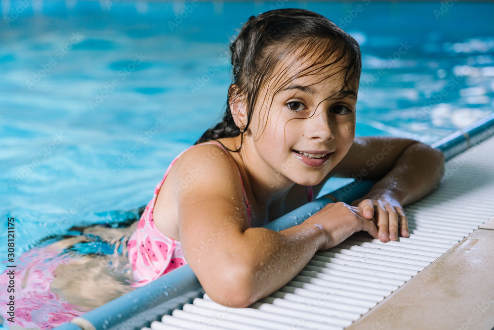 Portrait little girl having fun in indoor swimming-pool. The girl is ...