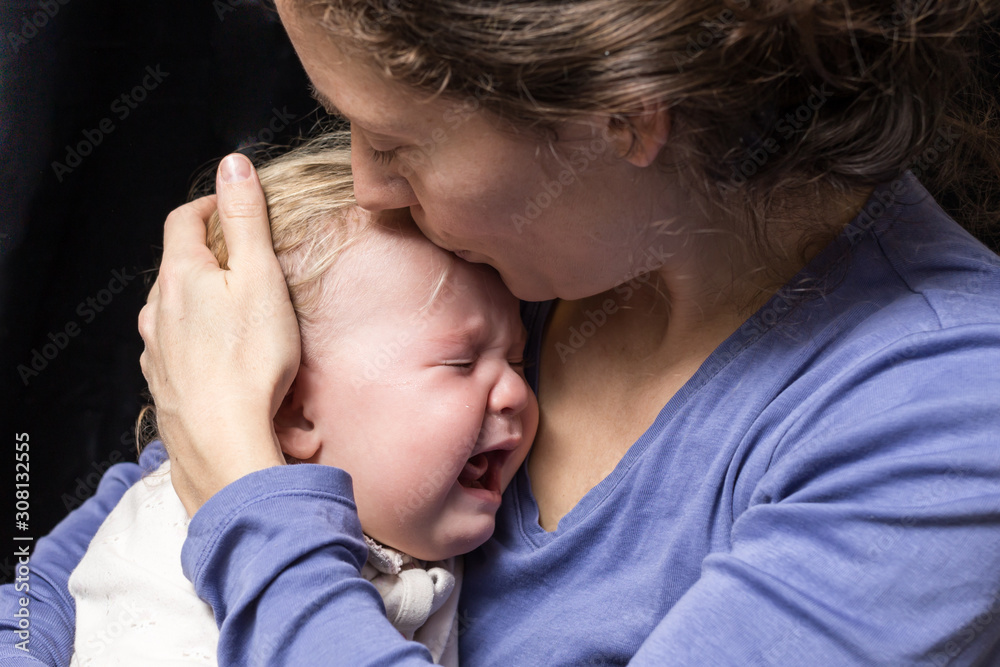 bébé pleure dans les bras de sa mère Stock-foto | Adobe Stock
