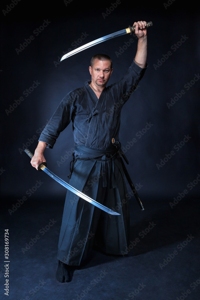 Man in a kimono holding two Samurai swords Stock Photo | Adobe Stock