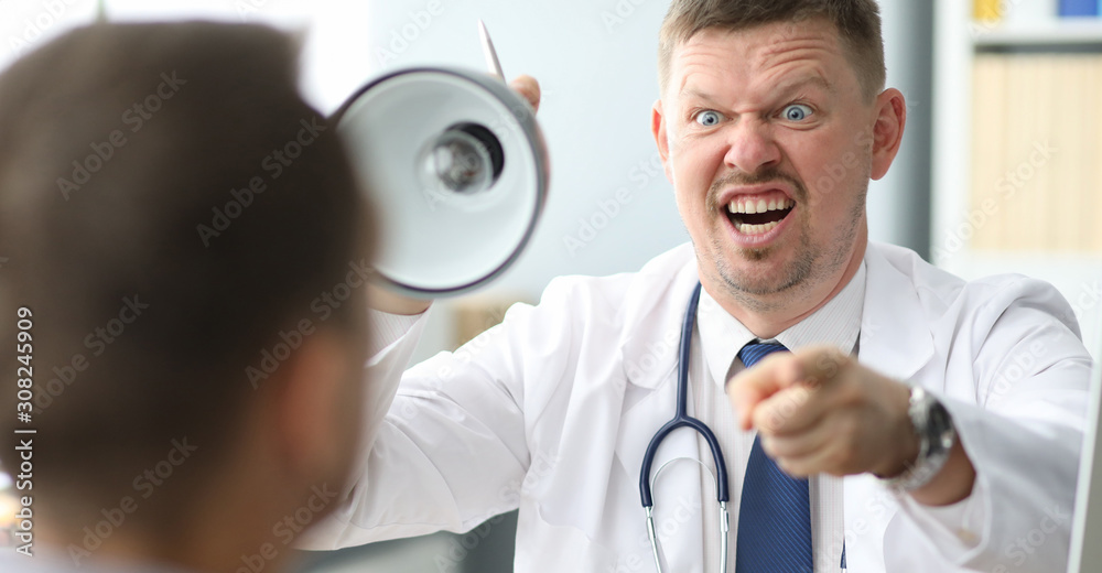 Angry doctor interrogates the patient, yelling at him, pointing to man ...