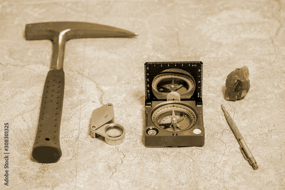 The tools of the geologist laid out on a topographic map. Background ...