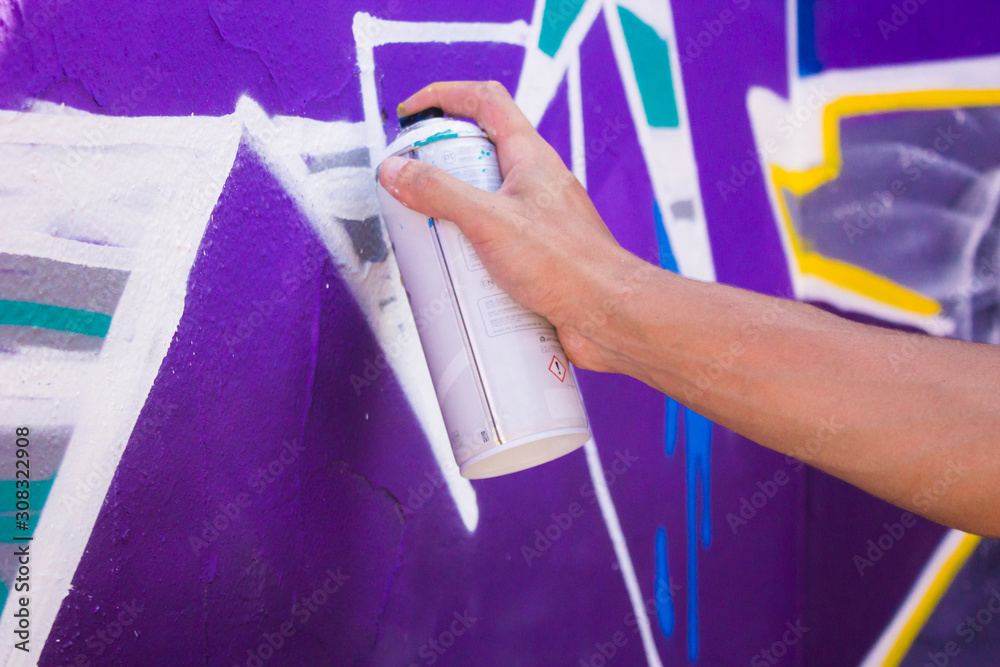 Graffiti artist painting with aerosol spray on the wall at Favela in ...