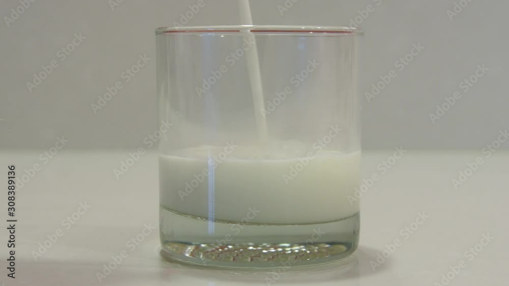 Video top view of clear glass being filled with milk, wood table ...