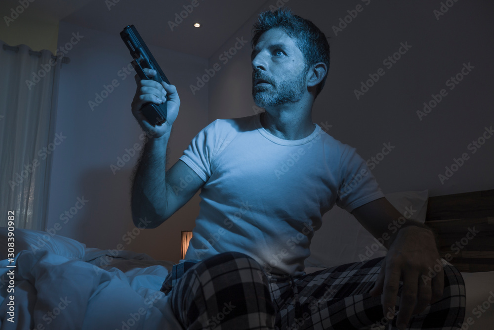 night edgy portrait of young stressed and paranoid American man sitting ...