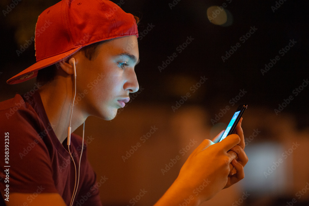 Close-up portrait of a young man with smartphone, on the city. Teenage ...